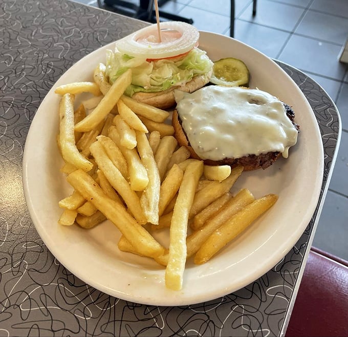 Golden-crisp fries flanking a cheeseburger that's wearing its melted cheese like a cozy blanket—comfort food that understands you better than your therapist.