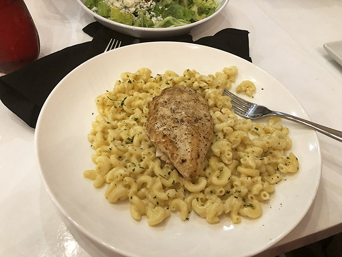 Mac and cheese transcends to art form here—perfectly al dente pasta swimming in creamy goodness, topped with herb-seasoned chicken that's begging for your attention.