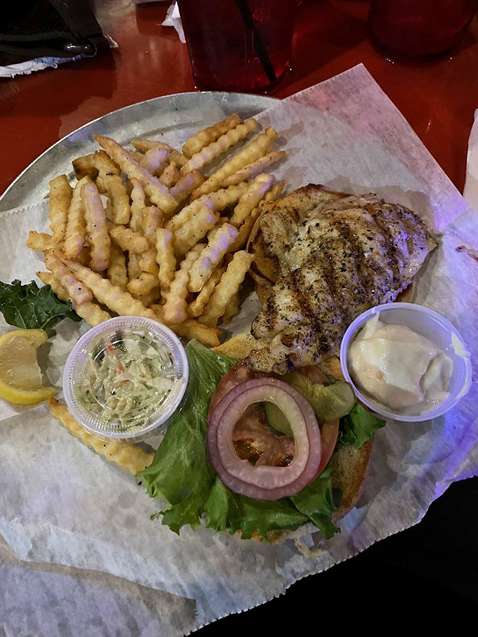 This isn't just a sandwich; it's seafood architecture. Perfectly seasoned grouper spilling beyond its bun borders with crispy fries standing by for backup.