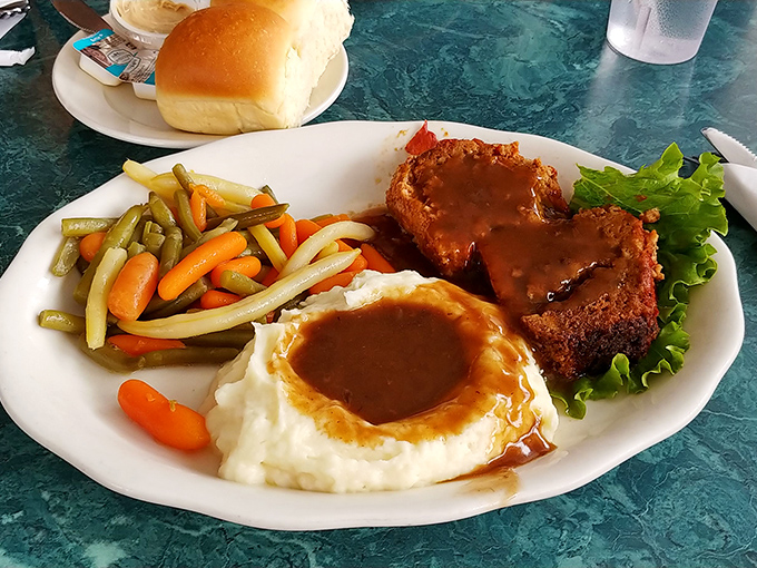 Behold the star attraction – meatloaf that would make your mother both jealous and proud, nestled in gravy that deserves its own fan club.