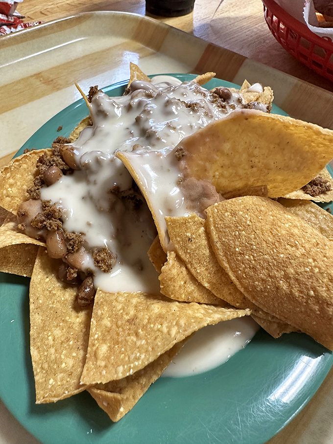 Behold the holy grail of nachos—where cheese sauce cascades over seasoned beef like a dairy waterfall of dreams.