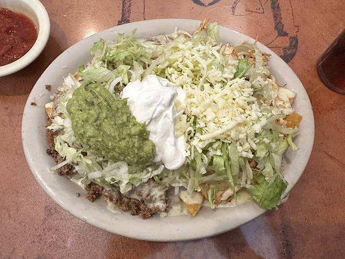 Layer upon glorious layer of crispy chips, seasoned beef, and fresh toppings—this isn't just a plate of nachos, it's an edible architecture masterpiece.