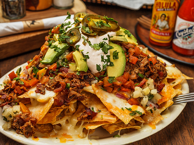 These nachos don't just have toppings—they have architecture. Every layer tells a story, with avocado slices standing like green sentinels guarding flavor treasure.