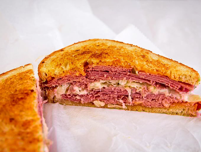 Behold the Reuben in its natural glory—layers of corned beef stacked with mathematical precision, the sauerkraut and Swiss creating a harmony that would make Mozart weep.