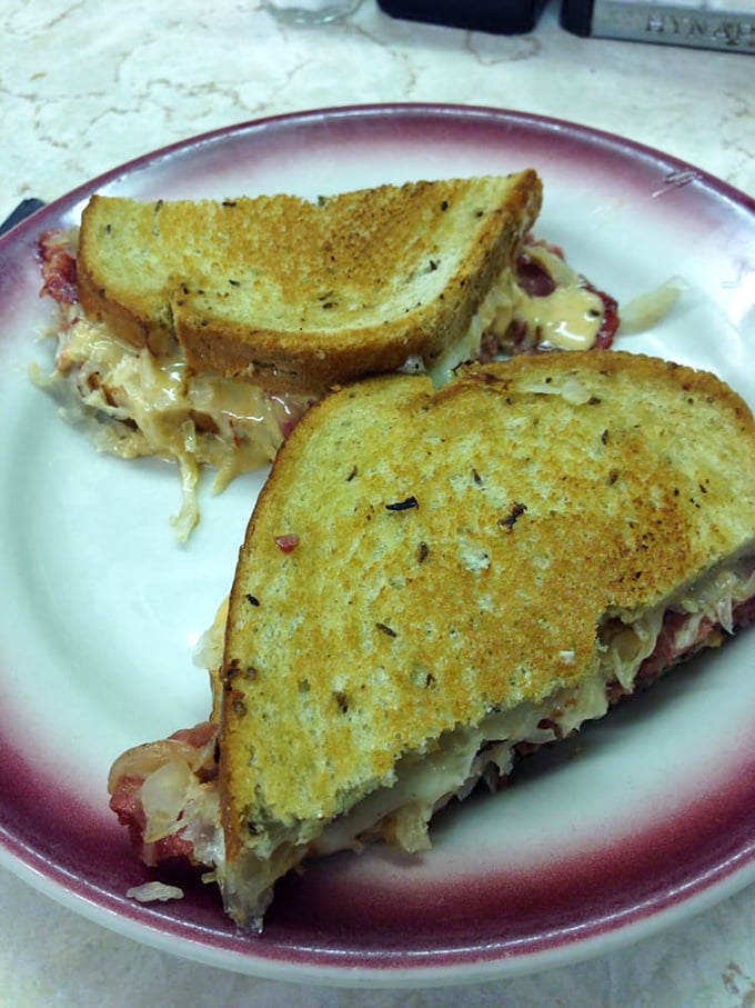 The Reuben in its natural habitat—perfectly grilled rye creating that symphony of crunch before surrendering to the tender corned beef within.