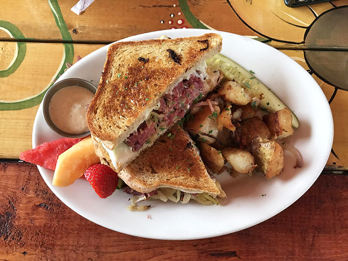 The legendary Reuben in its natural habitat—perfectly grilled, obscenely stuffed, and flanked by potatoes that didn't know they could taste this good.