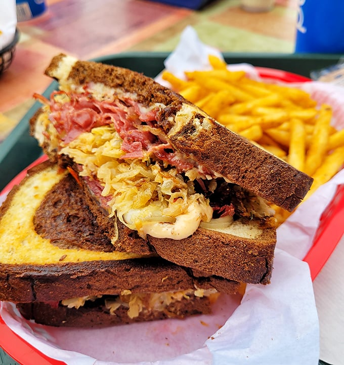 Behold the Reuben in its natural habitat—perfectly grilled rye, sauerkraut peeking out like it's playing hide-and-seek with that gloriously melted Swiss.