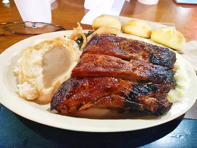 These ribs don't just fall off the bone—they practically jump onto your fork. Served with mashed potatoes and rolls that would make your grandma jealous.