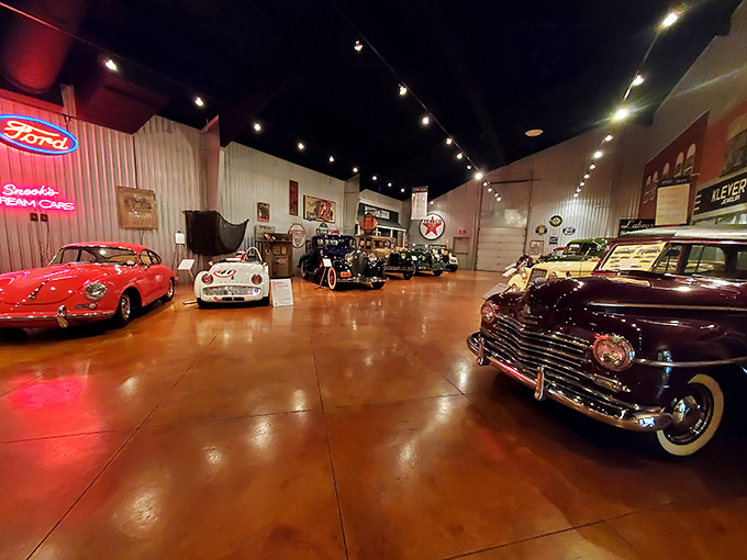 The showroom gleams with automotive royalty. That red beauty on the left? She's not just a car—she's the prom queen of the petroleum age.