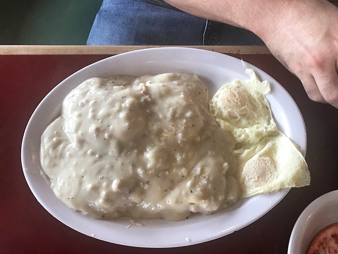 This country-fried steak swimming in pepper-flecked gravy isn't just breakfast—it's therapy on a plate, with eggs standing by for moral support.