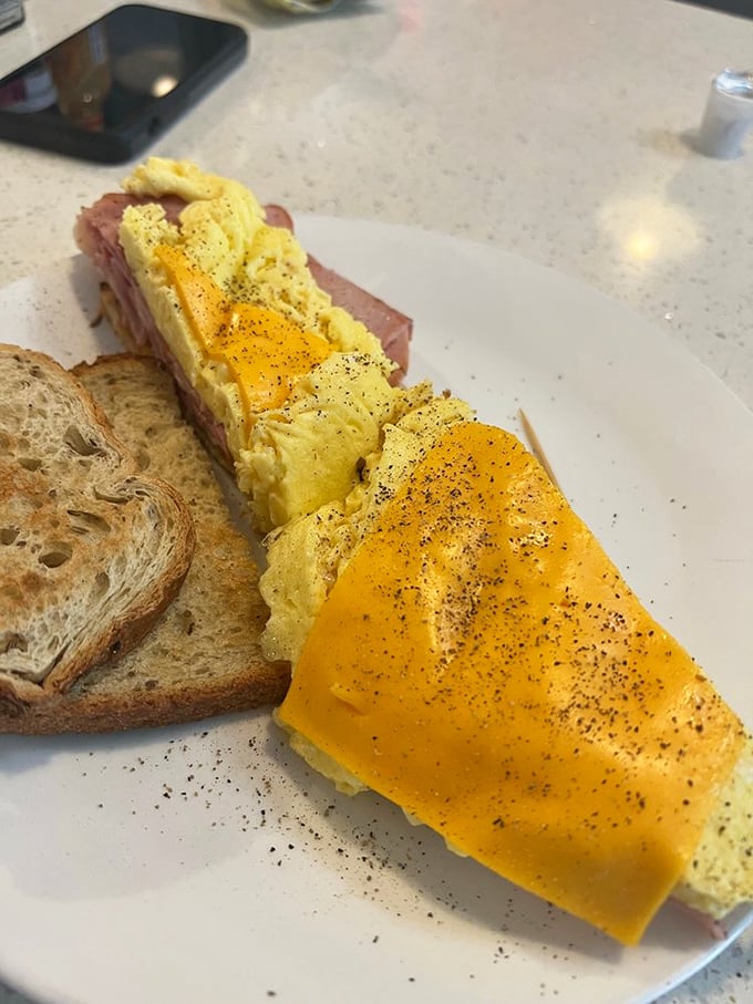 Behold the humble breakfast sandwich—where perfectly peppered eggs and ham create a morning masterpiece that makes fancy brunch spots seem unnecessarily complicated.