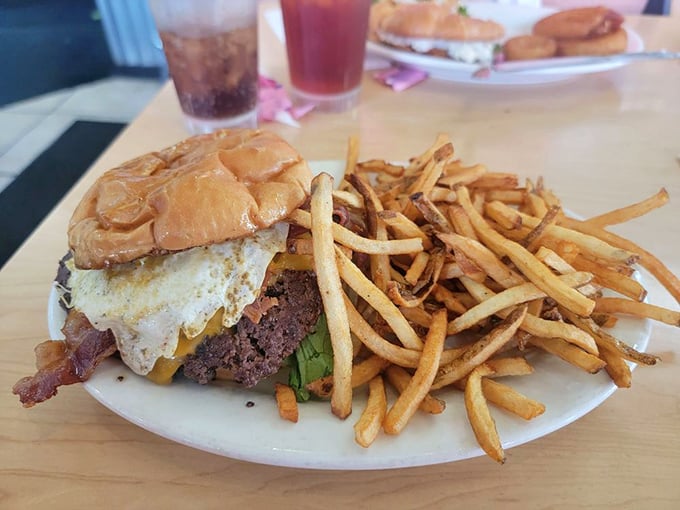 Behold the burger in its natural habitat—crowned with a perfect egg, surrounded by hand-cut fries, and practically begging to be photographed before devoured.