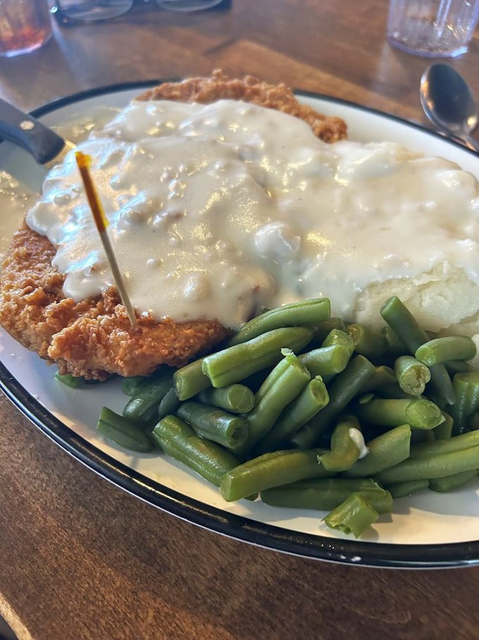 Behold the star of the show: chicken fried steak swimming in peppery gravy alongside fresh green beans—a plate that whispers "nap time" in your future.