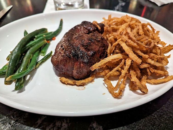 A perfectly cooked filet mignon flanked by crispy onion strings and vibrant green beans. This plate doesn't need Instagram filters—it's already food royalty.
