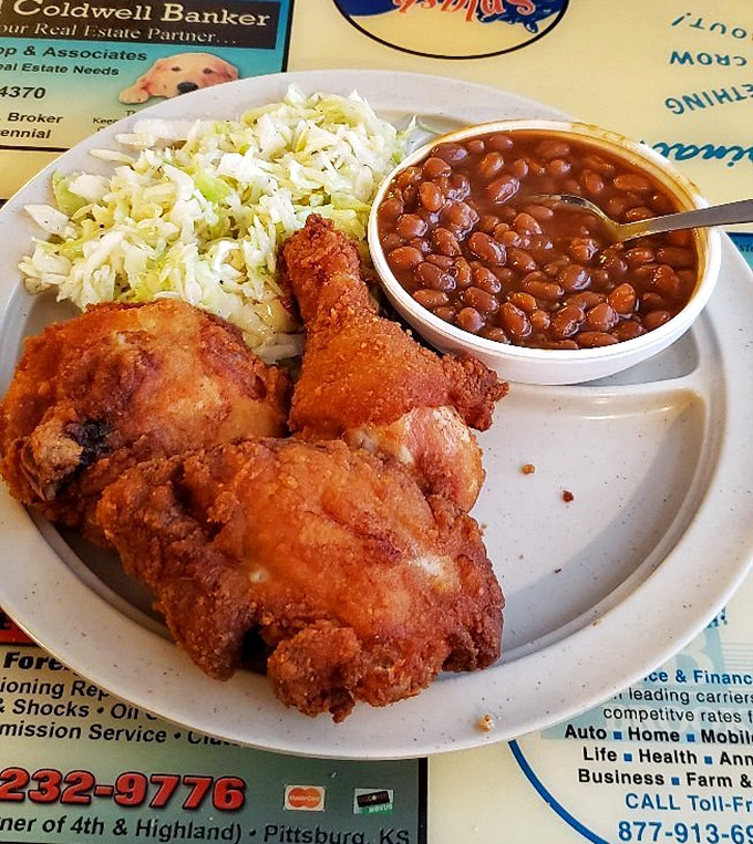 Golden-brown chicken with that perfect crunch sits alongside creamy coleslaw and baked beans – a holy trinity of heartland flavors.
