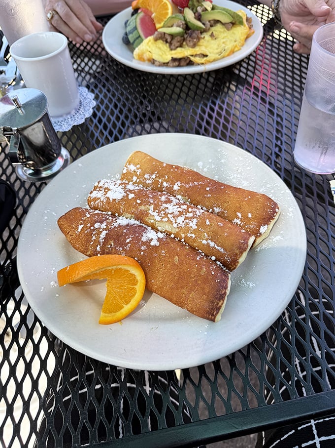 These aren't just crepes—they're edible sunshine dusted with powdered sugar. The orange slice isn't garnish; it's an exclamation point.