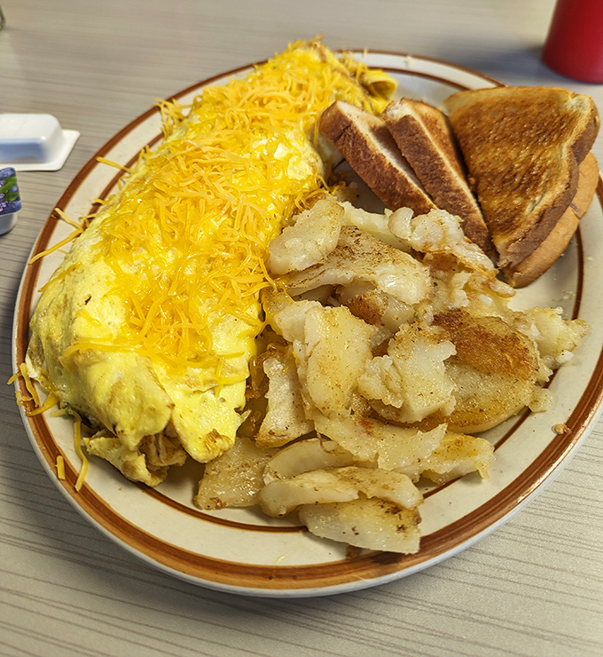 Behold the cheese omelet in its natural habitat—flanked by golden home fries and perfectly toasted bread. A breakfast trinity that never disappoints.