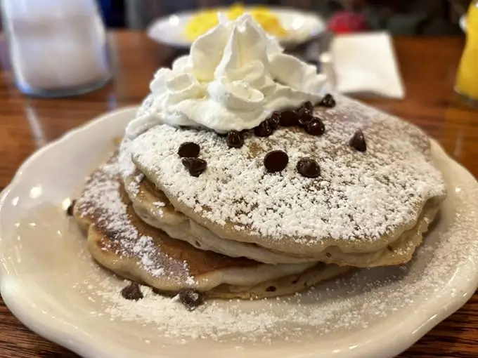 Chocolate chip pancakes with a mountain of whipped cream—because sometimes breakfast should feel like you're getting away with something deliciously naughty.
