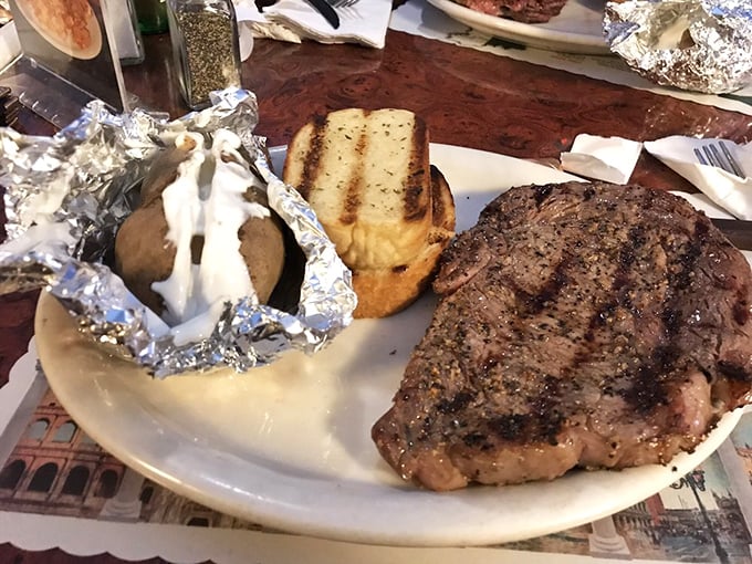 A perfectly grilled steak alongside a foil-wrapped baked potato loaded with the works – proof that some culinary equations never need solving.