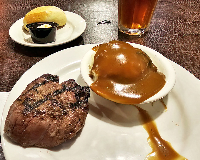 Simplicity perfected: a beautifully seared steak alongside a potato drowning happily in gravy—comfort food that speaks fluent Virginian.