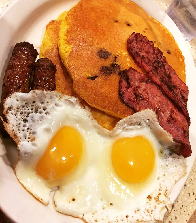 Sunny-side up eggs, golden pancakes, and perfectly crisped breakfast meats—the holy trinity of morning satisfaction that never disappoints.