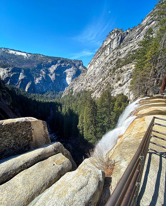 The top-of-falls perspective that makes you question gravity. That safety railing isn't a suggestion—it's the thin line between awesome photos and terrible decisions.