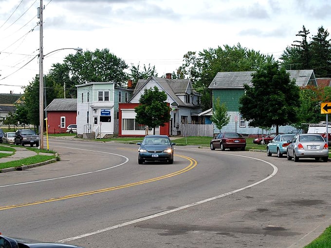 “A quiet street in Dunkirk, New York, lined with modest, colorful homes and parked cars, captures the charm of small-town living and a close-knit community atmosphere.”