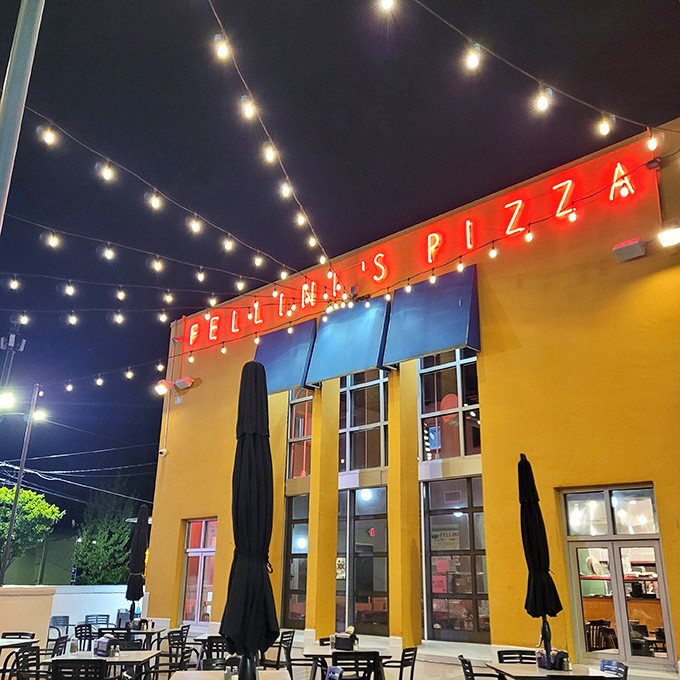 Felini's vibrant yellow building and twinkling lights create the perfect stage for their famously massive slices of pizza theater.