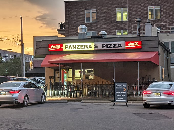 Panzera's sunset glow transforms this humble pizza spot into a red-awninged paradise where cheese dreams come true.