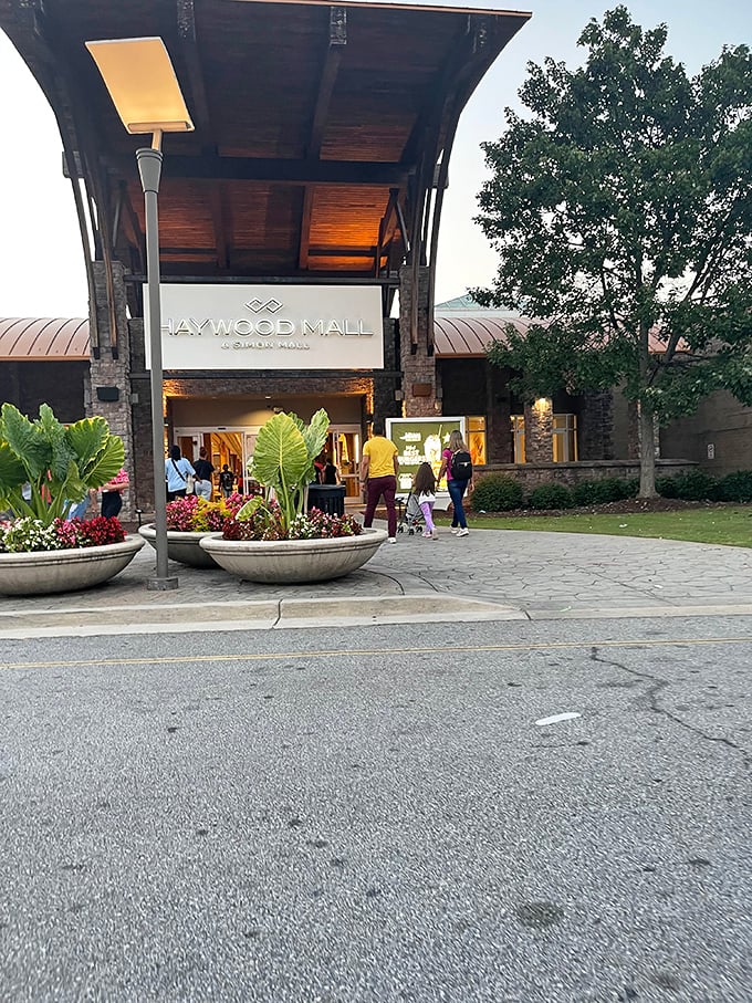 Haywood Mall's elegant wooden entrance welcomes evening shoppers with warm lighting and the promise of retail adventures inside.