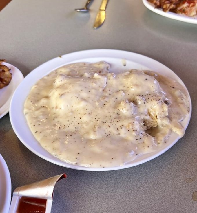 This isn't just gravy—it's a peppery, sausage-studded blanket lovingly tucked around a biscuit that clearly had a proper upbringing in a real kitchen.