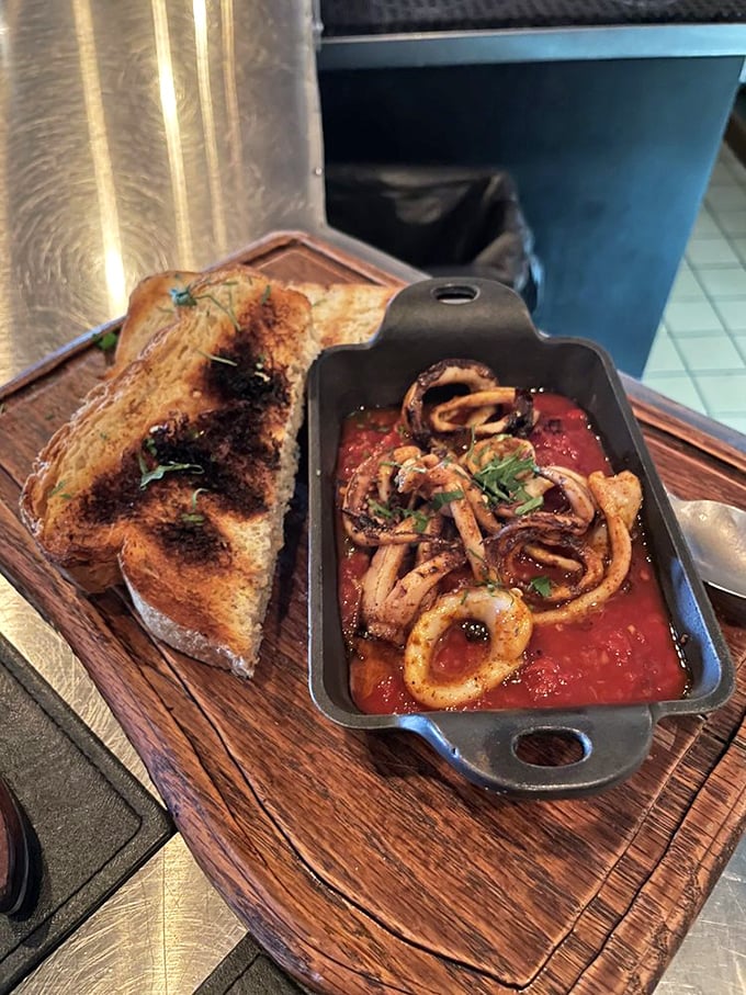 Calamari swimming in vibrant tomato sauce with charred bread for dipping—proof that seafood this fresh doesn't need a fancy introduction.