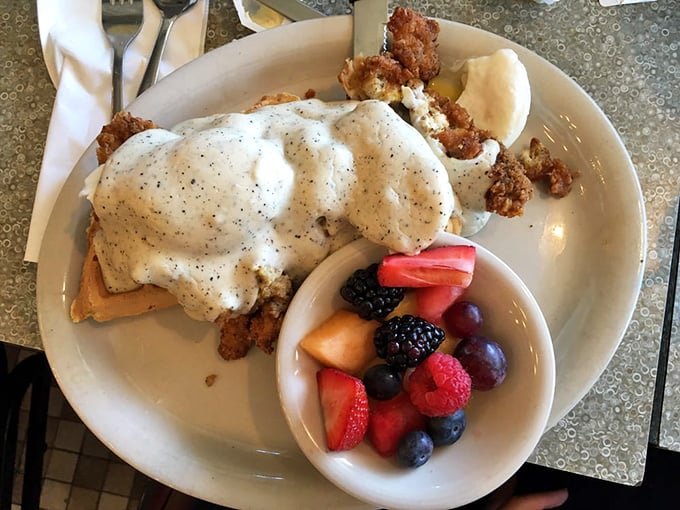 Breakfast innovation at its finest—chicken and waffles benedict with fresh fruit. It's what breakfast dreams about when breakfast goes to sleep.