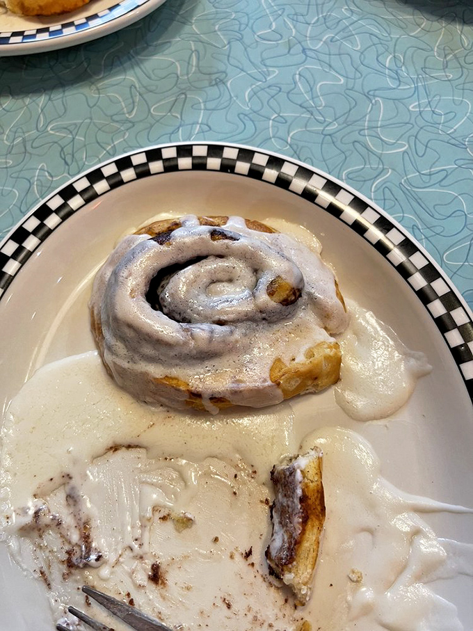 This isn't just any cinnamon roll—it's the reason elastic waistbands were invented. Swimming in icing that melts into every warm, cinnamon-spiced crevice.
