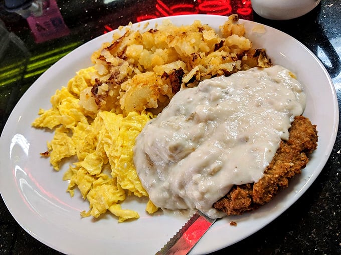Country fried steak smothered in gravy alongside sunny scrambled eggs and crispy potatoes—the breakfast trifecta that makes mornings worthwhile.