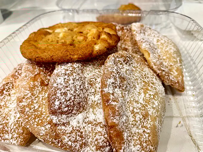 Golden-brown empanadas dusted with powdered sugar alongside a classic cookie—proof that heaven exists and it's made of pastry.