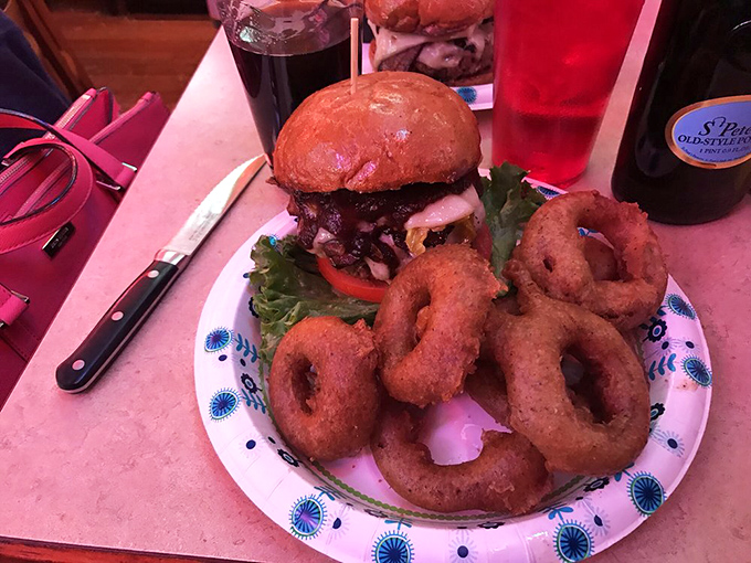 The onion rings form a golden halo around this burger that's not just a meal – it's a commitment to excellence and stretchy pants.