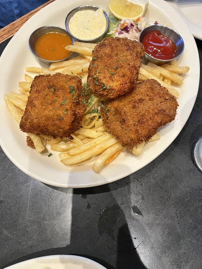 Three perfectly fried fish fillets standing at attention, ready to be dunked in an array of sauces. This isn't just fish and chips—it's an edible art installation.