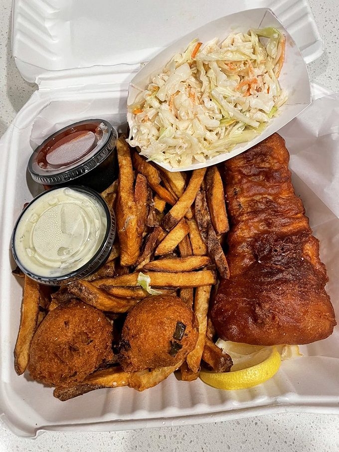 This isn't just fish and chips—it's edible architecture: crispy cod fortress, hand-cut fry scaffolding, and hushpuppy sentinels standing guard.