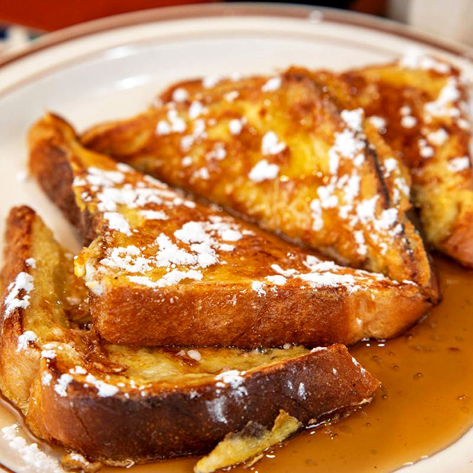 French toast that's achieved the perfect balance of crispy exterior and custardy interior, swimming in syrup and dusted with powdered sugar like a sweet winter morning.