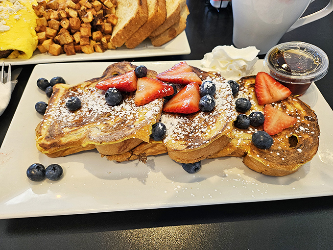 French toast that deserves its own Instagram account—golden perfection crowned with fresh berries that pop against powdered sugar like edible confetti.