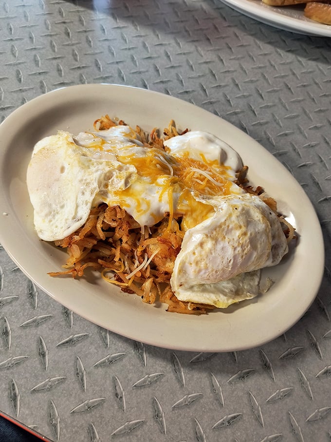 Breakfast architecture at its finest—crispy hash browns supporting perfectly cooked eggs, all smothered in cheese. The Hobo Stack is humble nobility on a plate.