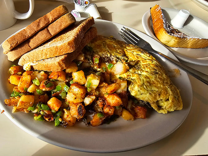 The holy trinity of breakfast perfection: a fluffy omelet that defies physics, home fries with just-right crispness, and toast standing by for yolk-sopping duty.