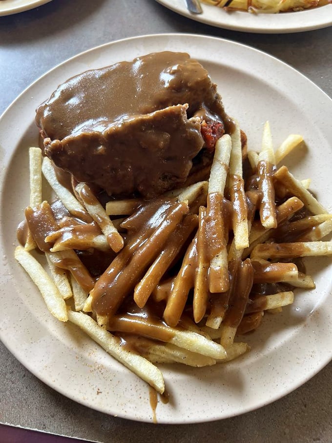 Gravy isn't a condiment here—it's practically a beverage, generously blanketing this meatloaf sandwich and transforming ordinary fries into vehicles for deliciousness.