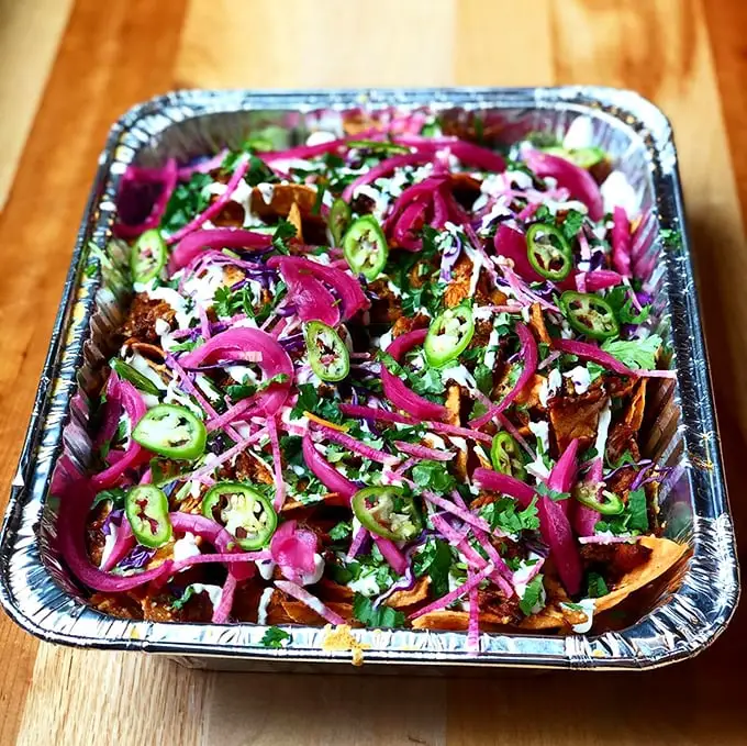 A fiesta of colors and textures—bright pickled onions, fresh jalapeños, and herbs dance atop perfectly layered chips. Nacho average appetizer!