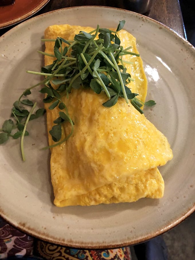 An omelet so perfectly executed it deserves its own cooking show. The pea shoots aren't just garnish—they're the supporting actors that steal the scene.