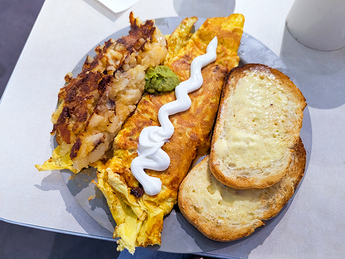 This omelet doesn't just sit on the plate—it commands it. Those lyonnaise potatoes aren't a side dish; they're co-stars in this breakfast drama.