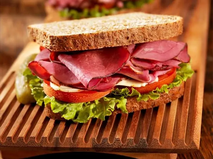 Layers of thinly-sliced pastrami nestled between garden-fresh veggies and hearty rye—a sandwich architecture that deserves its own blueprint.