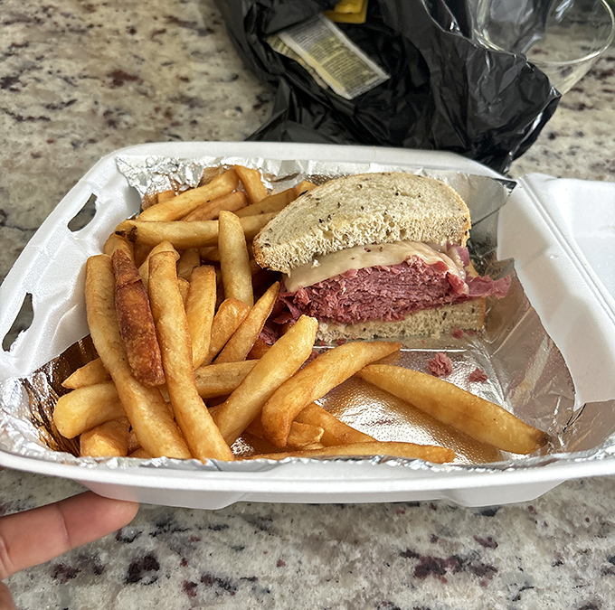 The takeout Reuben comes packed with enough corned beef to feed a small delegation, proving good things really do come in aluminum containers.