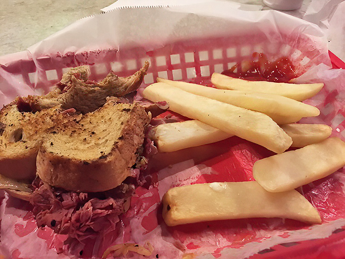 The classic presentation – sandwich, fries, red-checkered paper – reminds us that sometimes the simplest pleasures are the most satisfying.